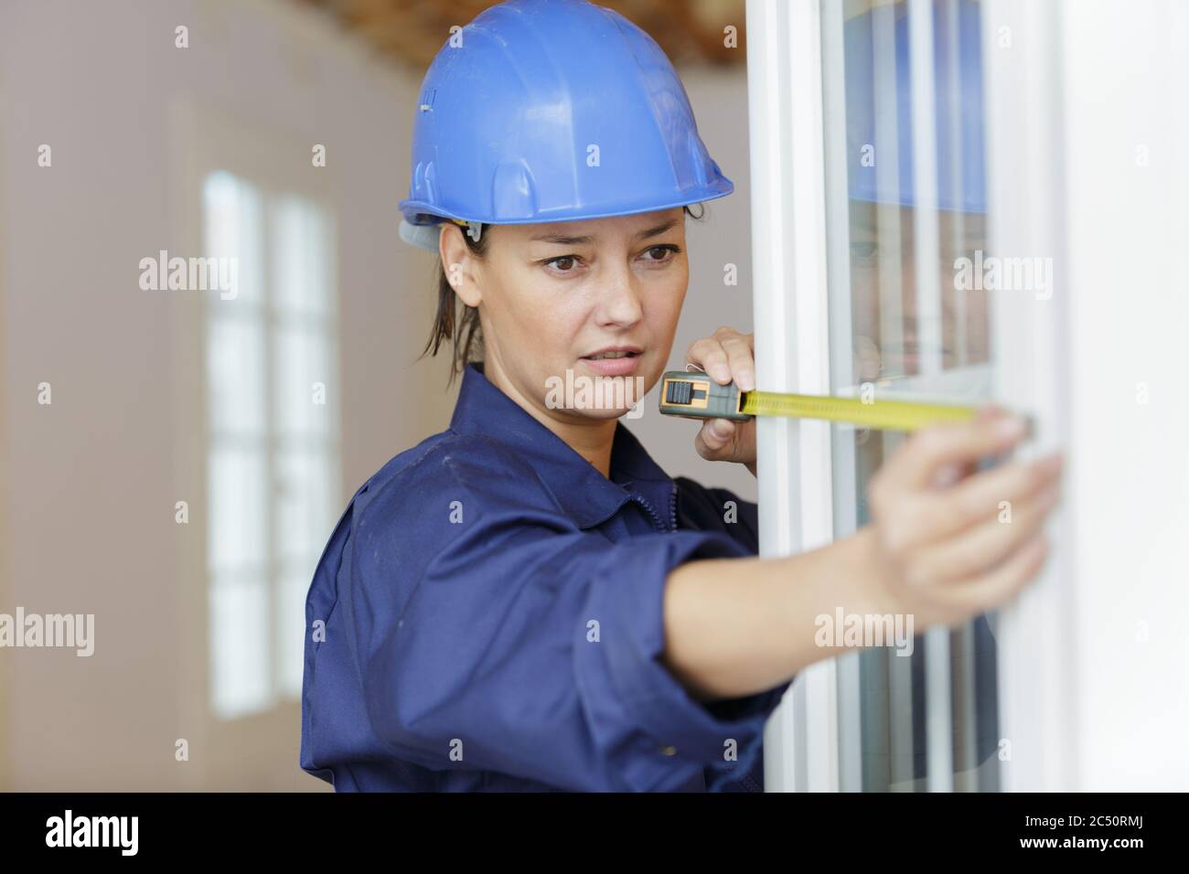 a workwoman measuring pvc window Stock Photo - Alamy