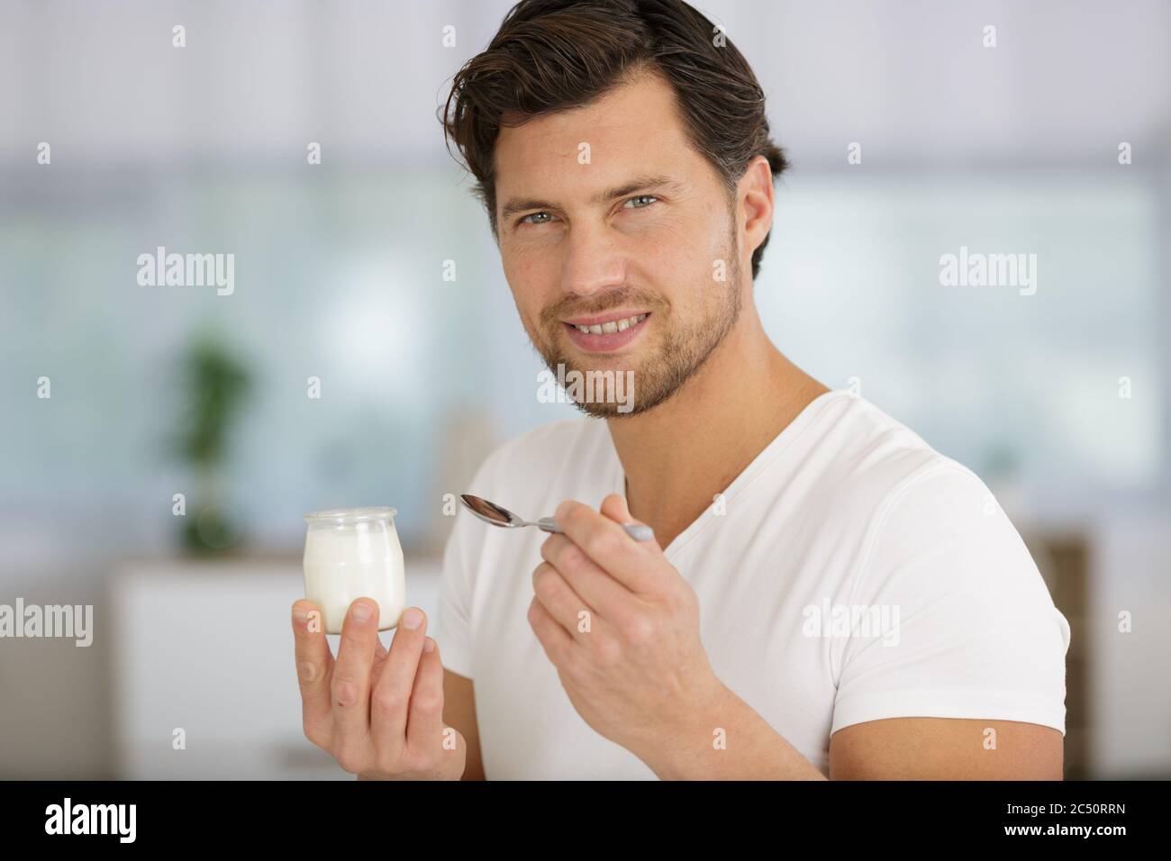 man is eating a yogurt Stock Photo - Alamy
