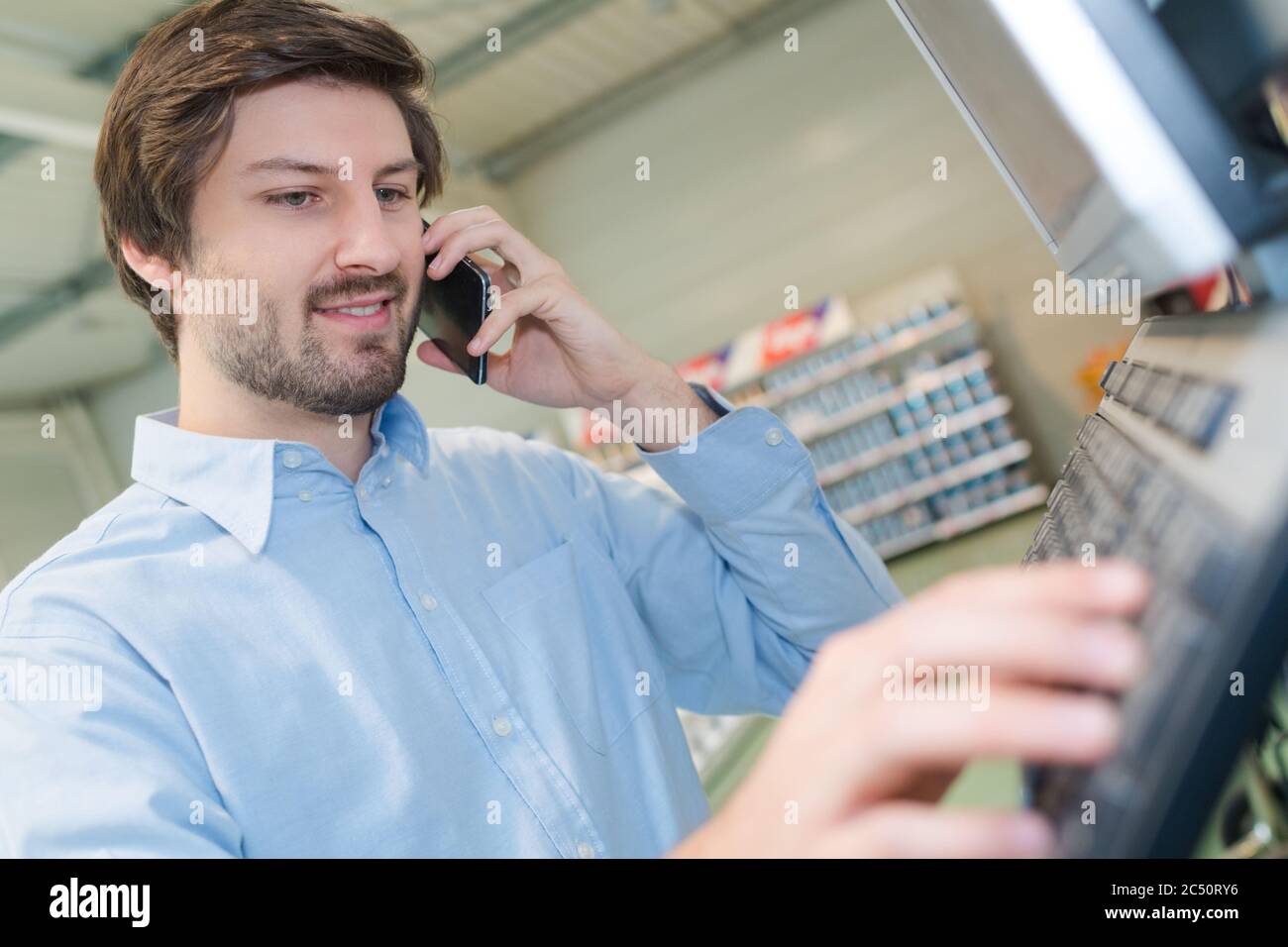 worker programming computer while talking on telephone Stock Photo - Alamy