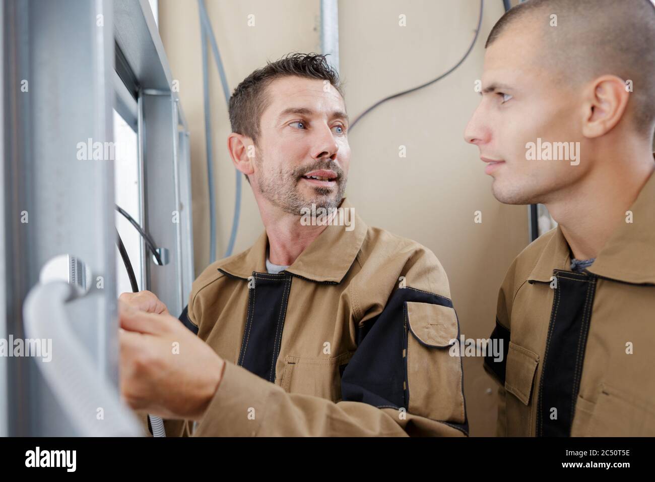 portrait of builder and apprentice talking indoors Stock Photo - Alamy