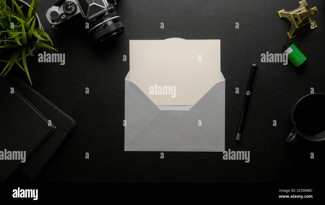 Overhead shot of open mock-up greeting card with grey envelope on dark ...