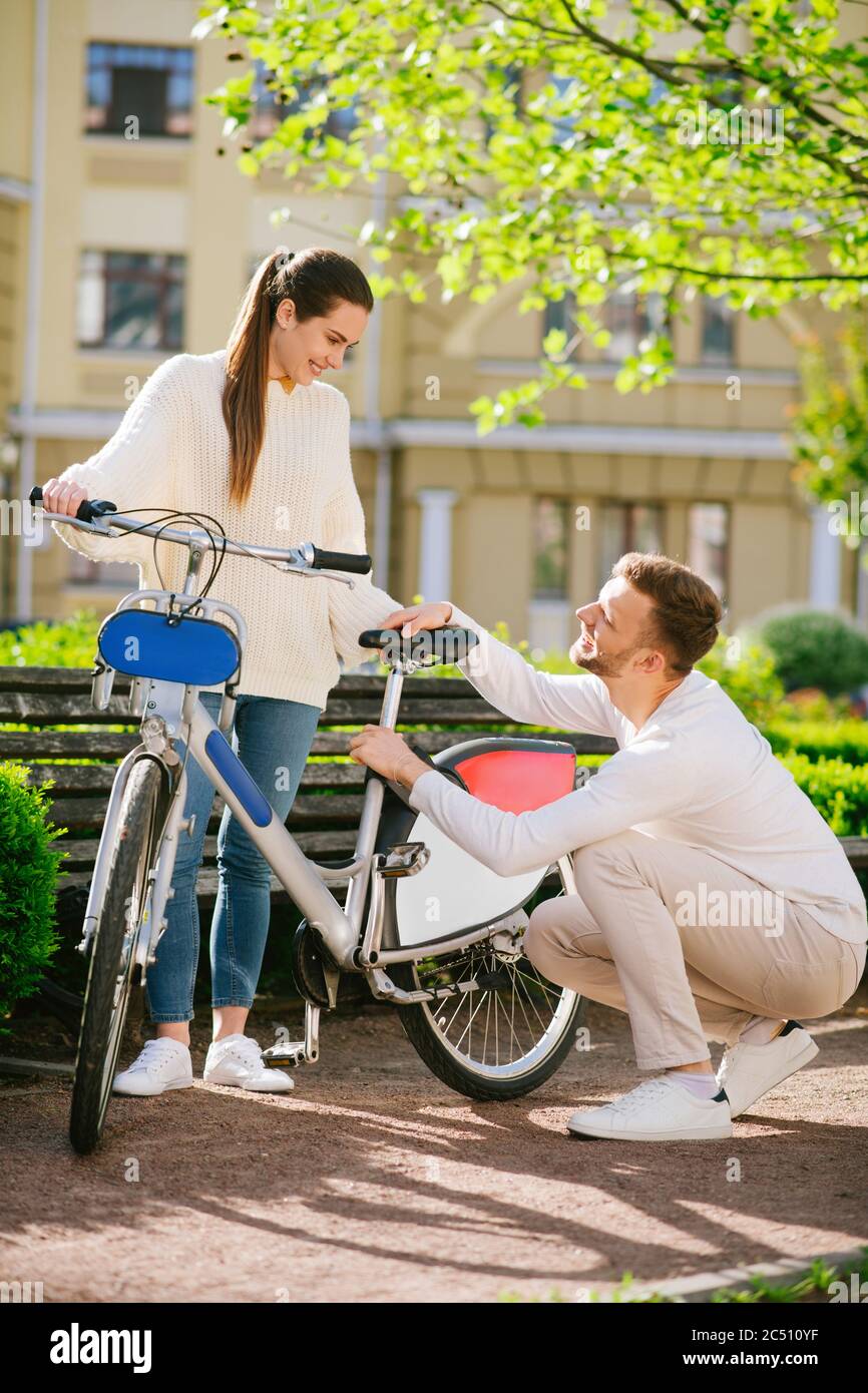 Woman supporting bike and man crouching down Stock Photo - Alamy