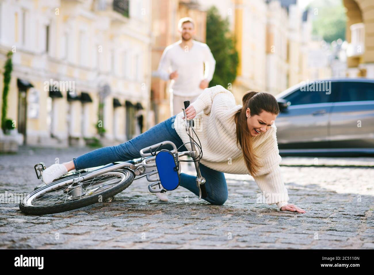 Woman on city street falling with bike Stock Photo - Alamy