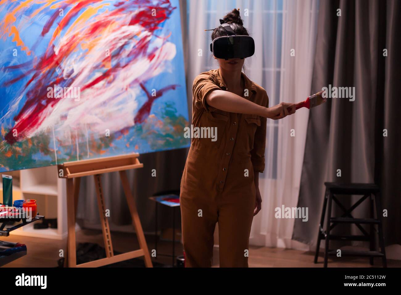 Painter using virtual reality headset in art studio creating a ...