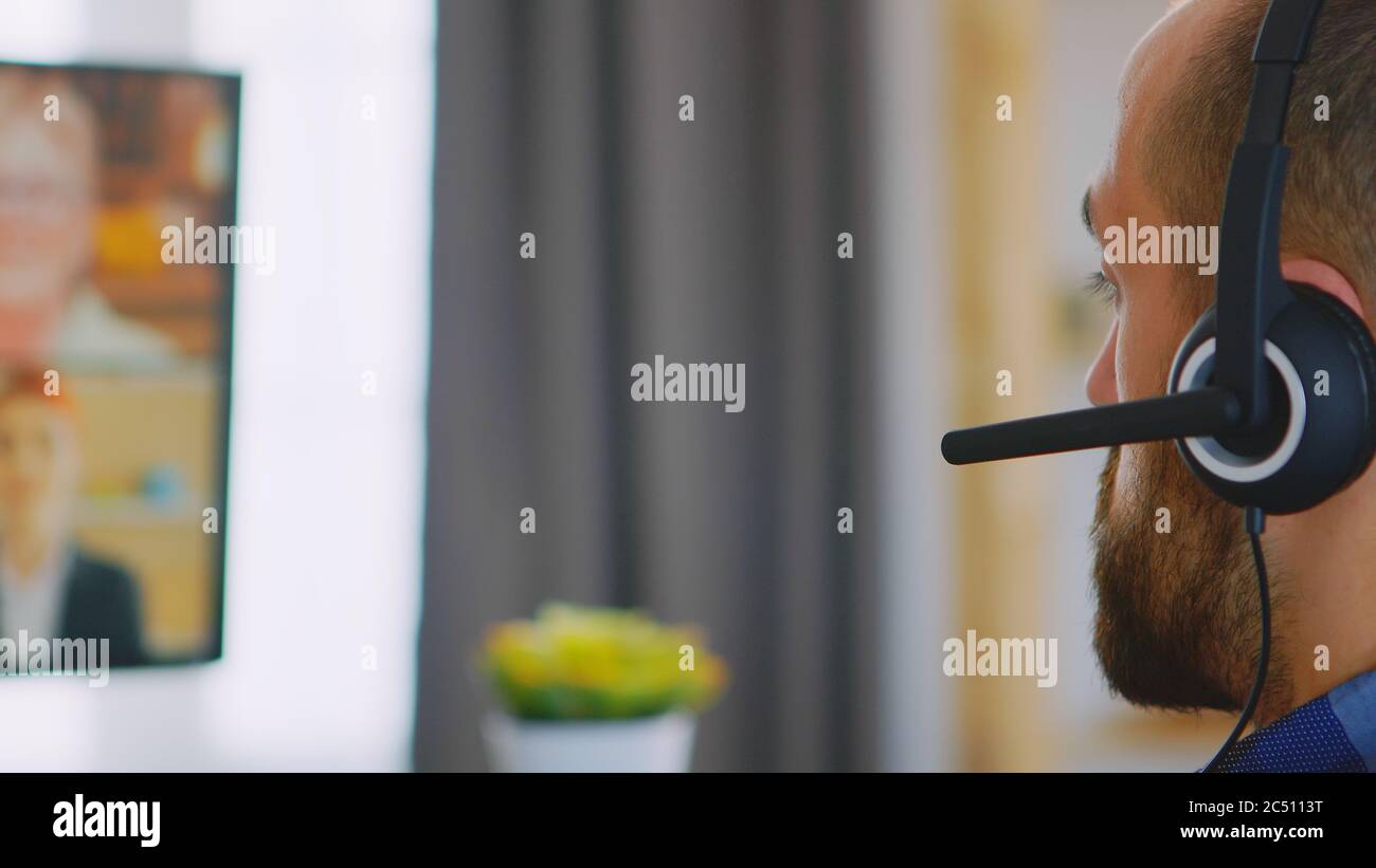 Freelancer using headphones during a call from home Stock Photo - Alamy