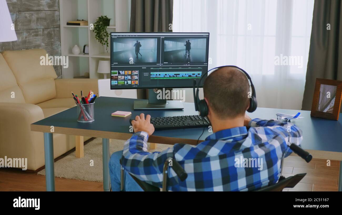 Invalid man in wheelchair editing a video using post production ...