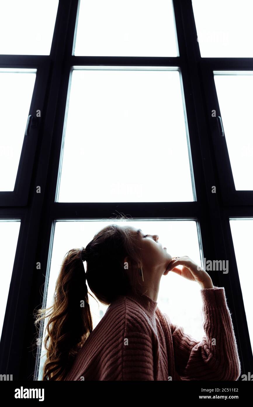 Girl is sitting opposite the window. The girls hair is pulled back in a ...