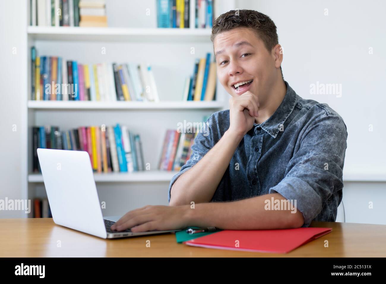 Laughing german computer science student working at computer indoors at ...