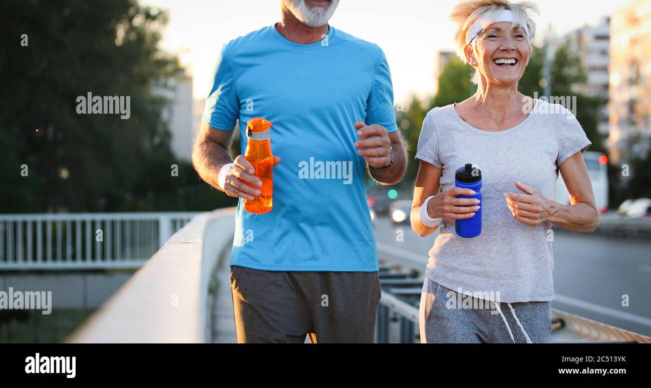 City running couple jogging outside. Senior couple runners training ...