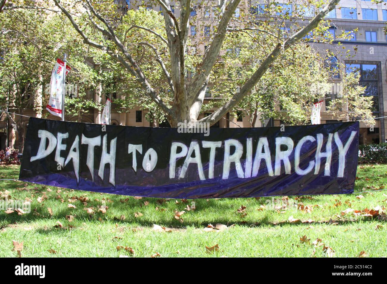 A banner saying, ‘Death to patriarchy’ is hung between two trees in ...