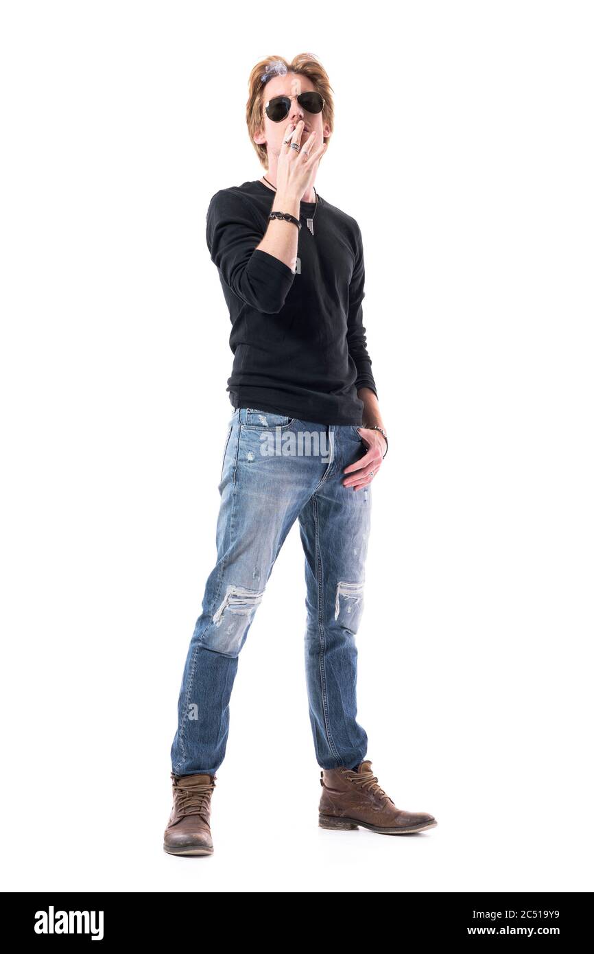 Young handsome red hair rocker style man smoking cigarette looking at ...