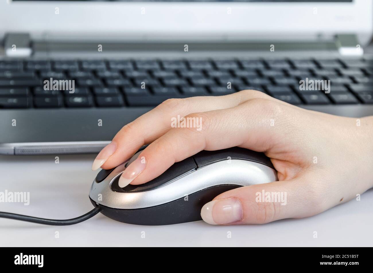 Female hand using computer mouse in front of laptop Stock Photo - Alamy