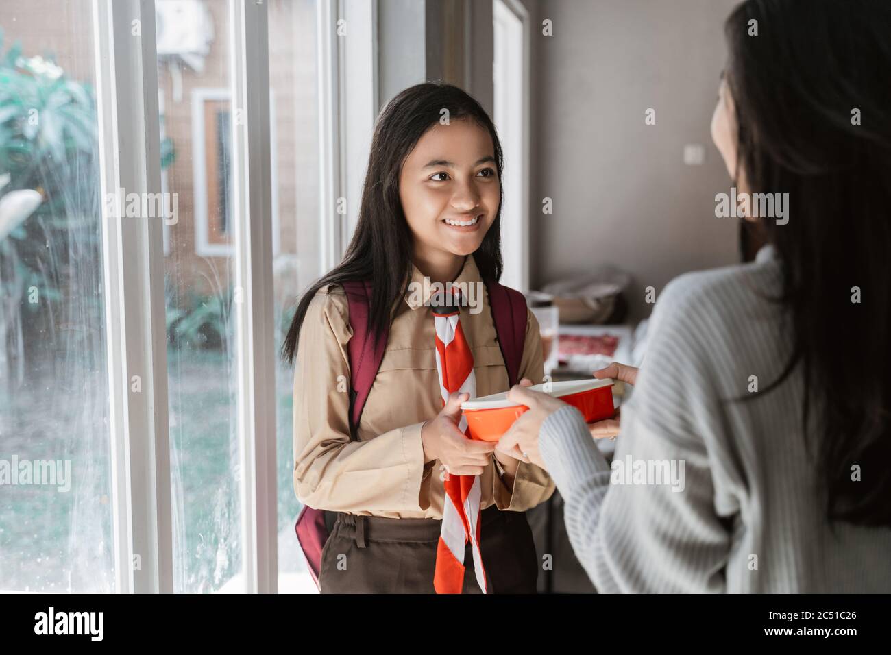 mother help preparing lunch box to her daughter junior high school ...