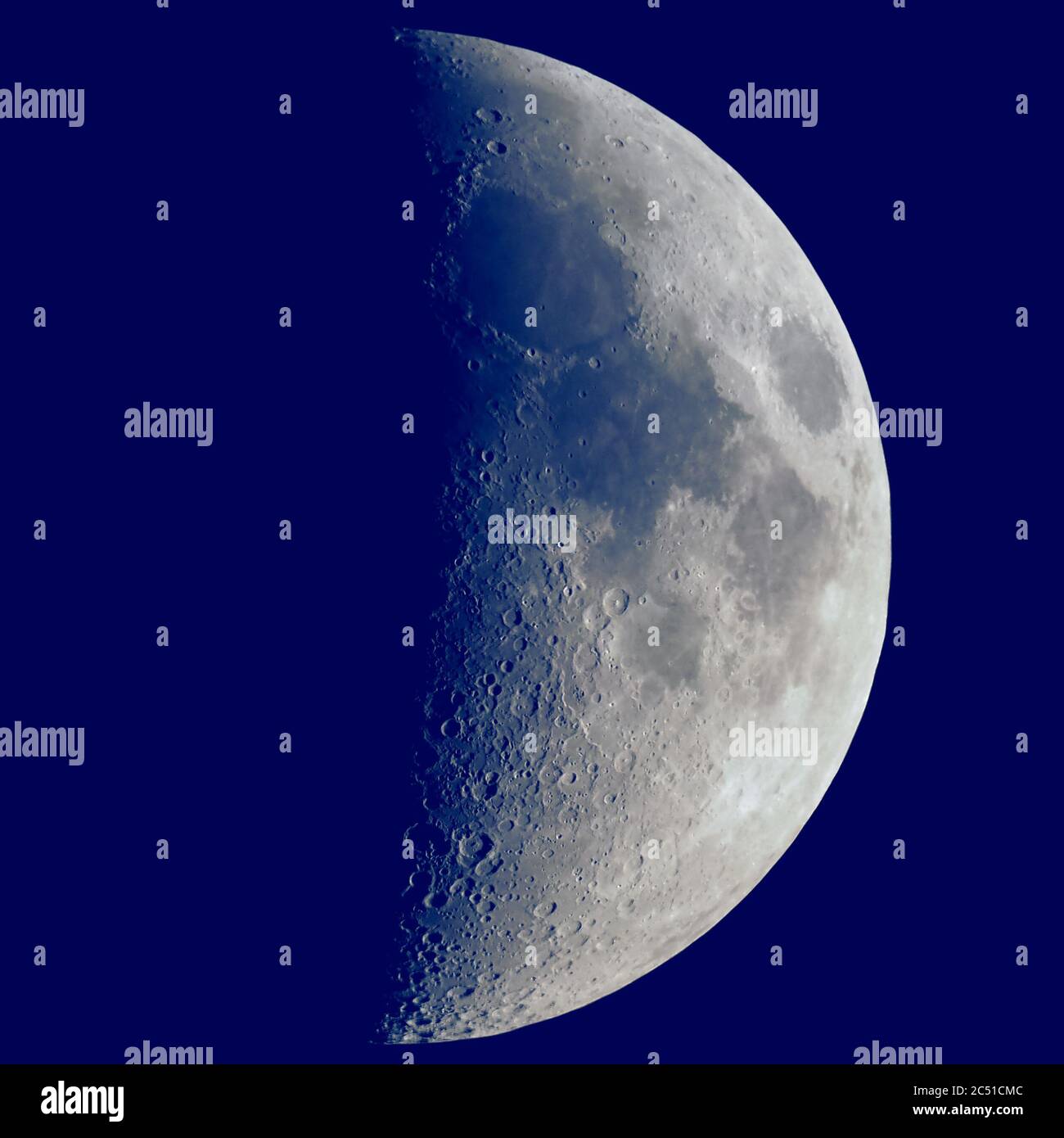 First quarter moon seen with an astronomical telescope, dark blue sky ...
