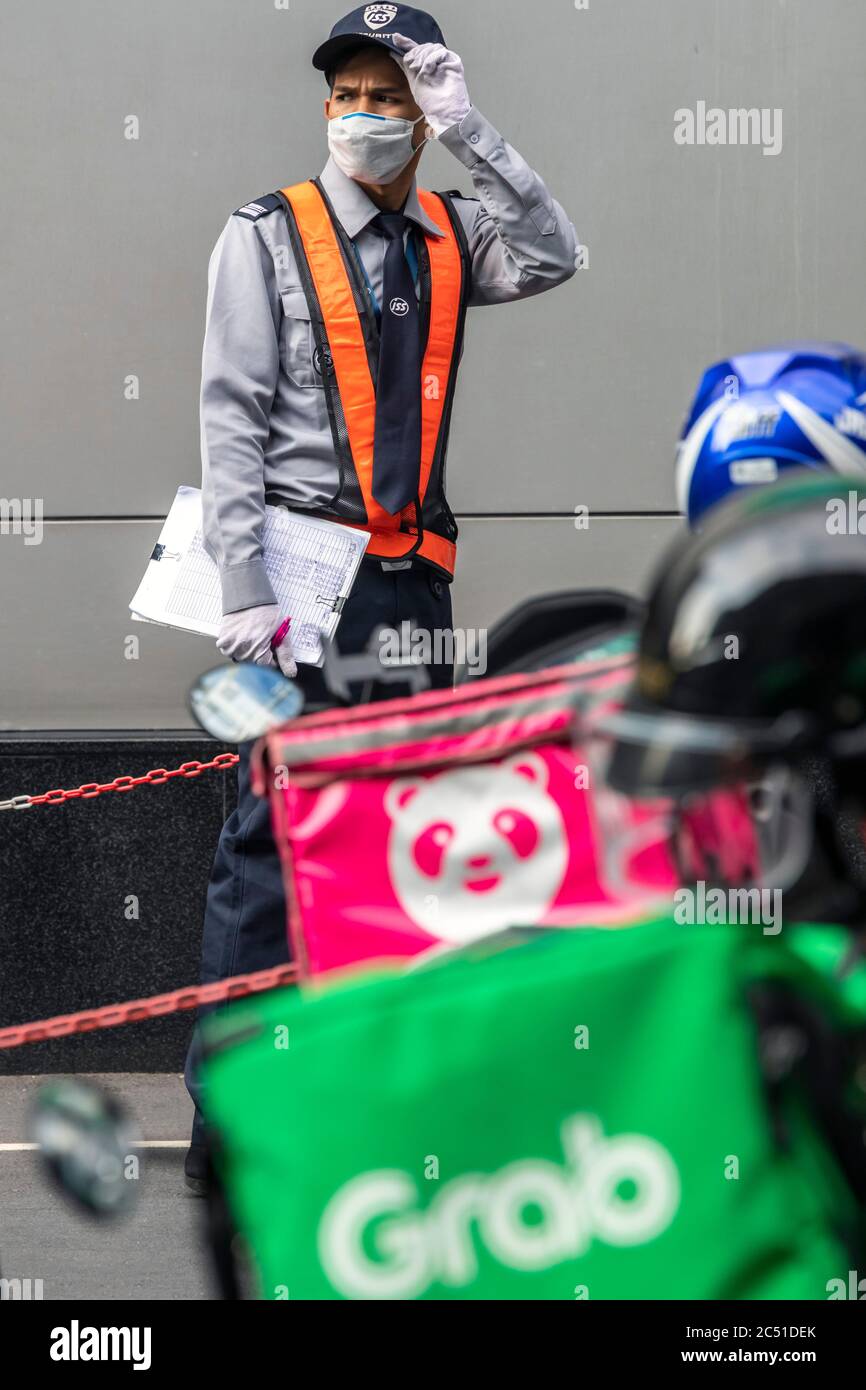 Security guard with face mask beside, Grab and Food Panda delivery ...