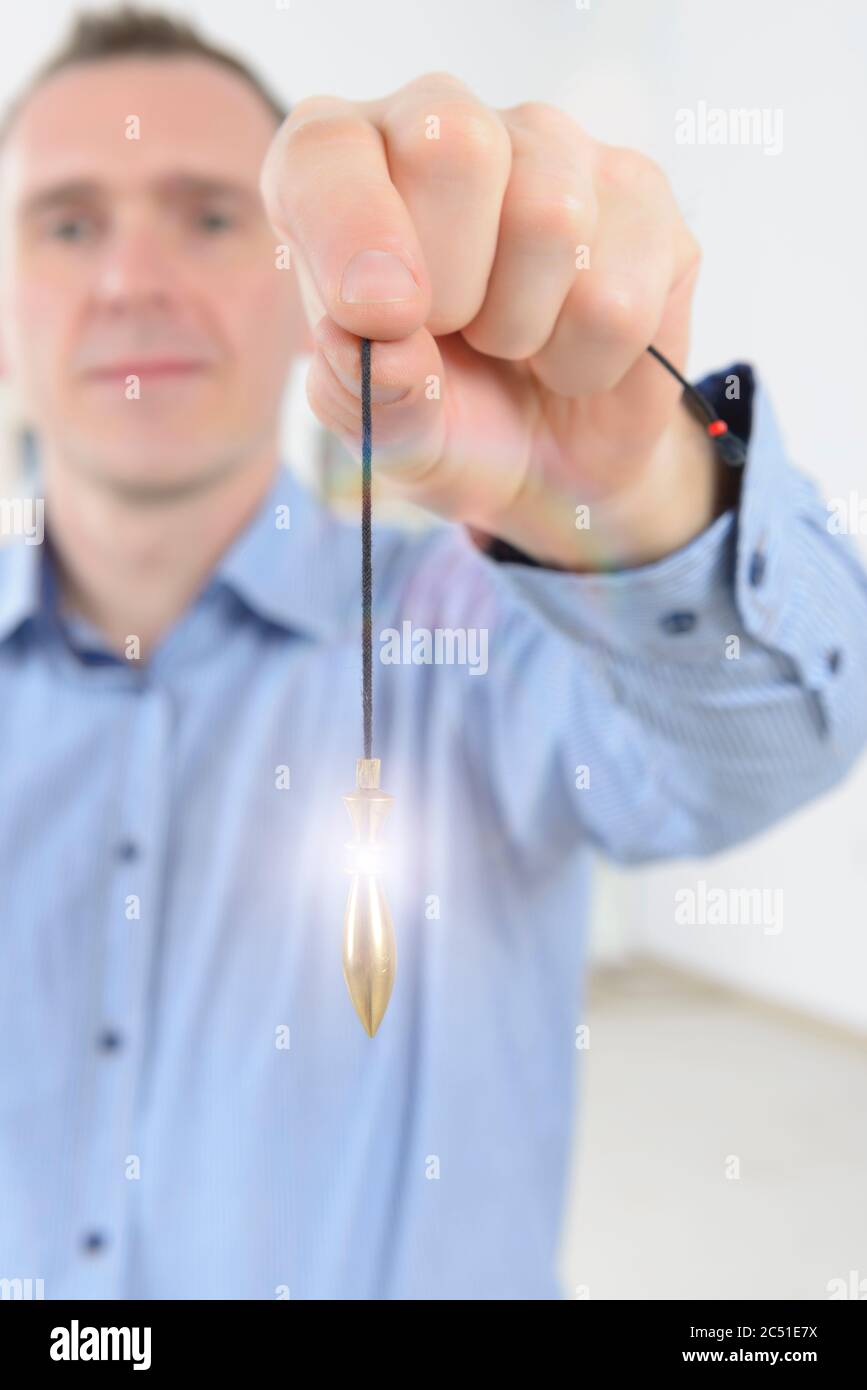 Hand with pendulum, tool for dowsing Stock Photo - Alamy