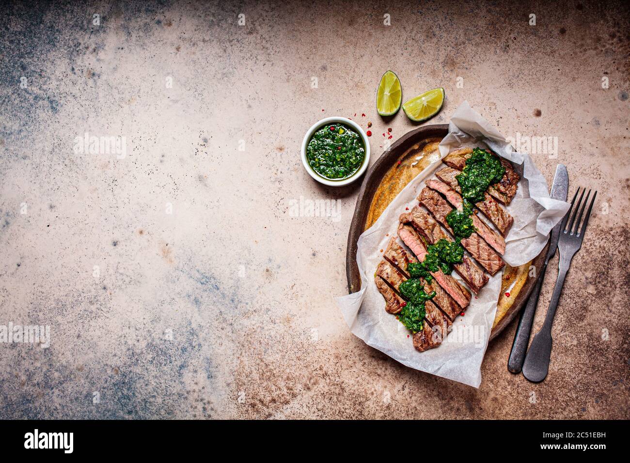 Sliced grilled beef steak with chimichurri sauce on a dark dish, dark ...