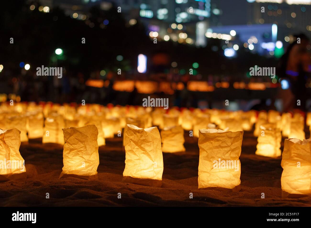 Night view of a row of candlelit paper lanterns on a beach with an ...