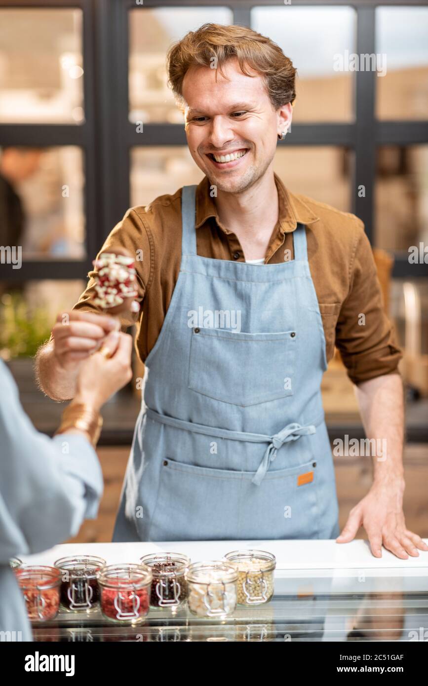 Portrait of a cheerful salesman in uniform selling ice cream at the ...