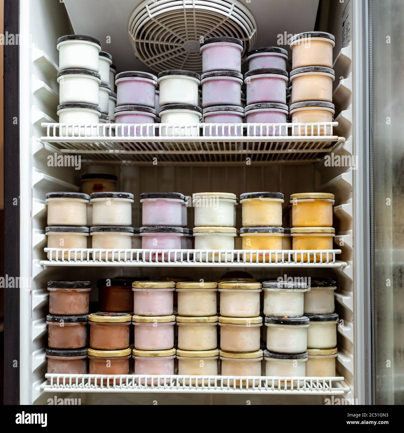 Fridge full of the ice cream packed in jars with a different flavors ...