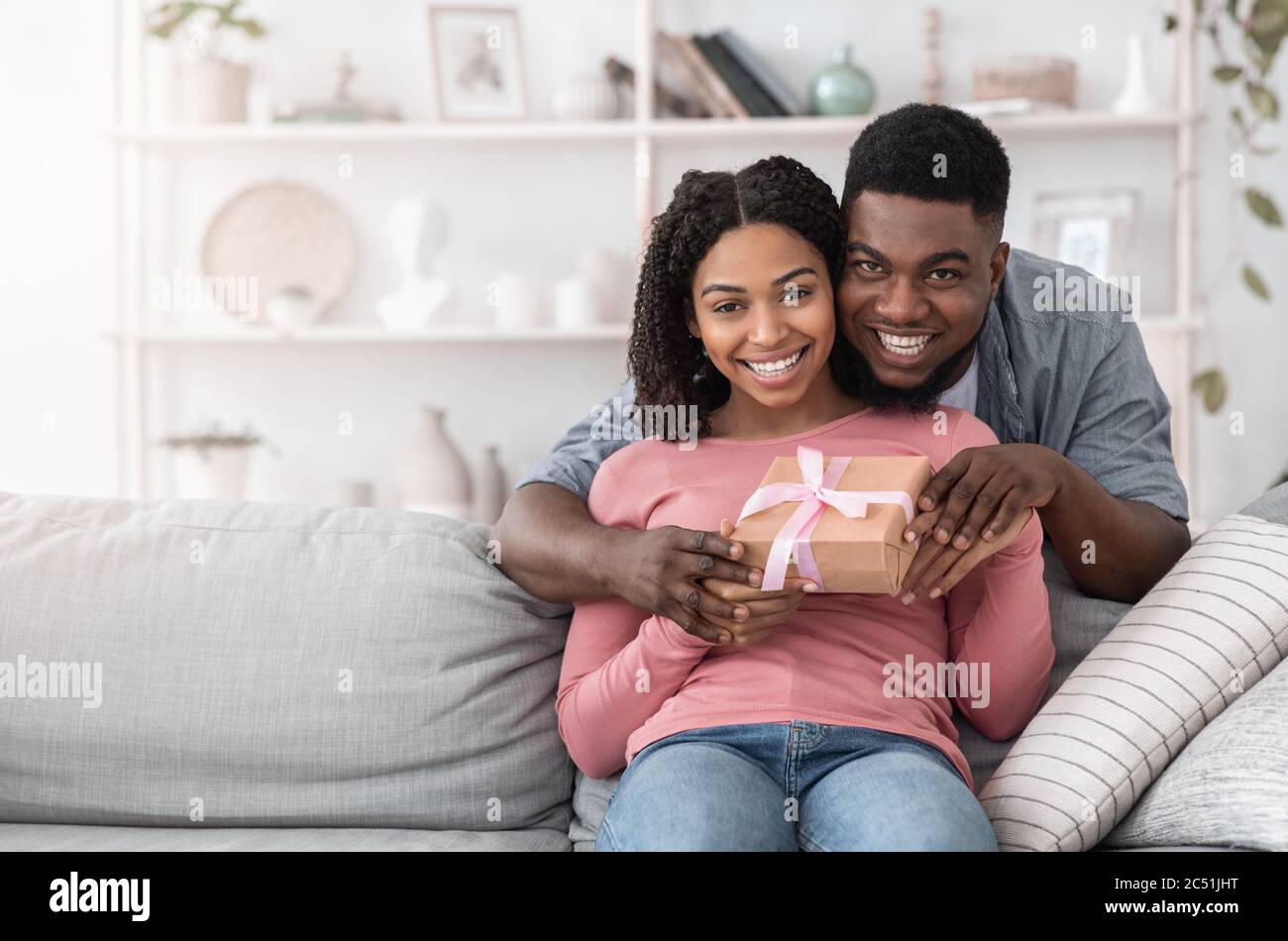 Black couple in love posing with present box on couch at home Stock ...