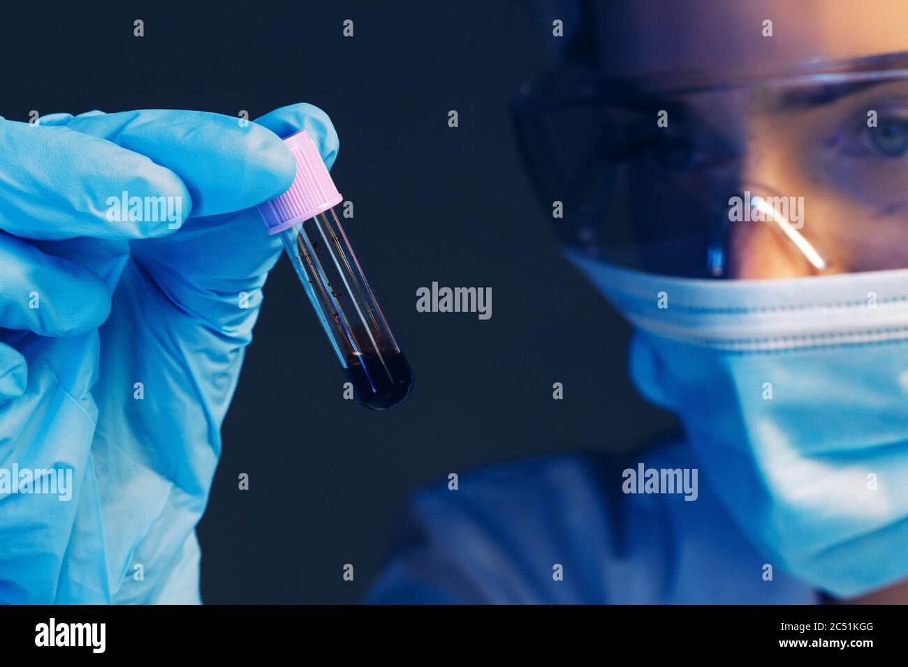 Female scientist looking at test tube with blood sample in laboratory ...