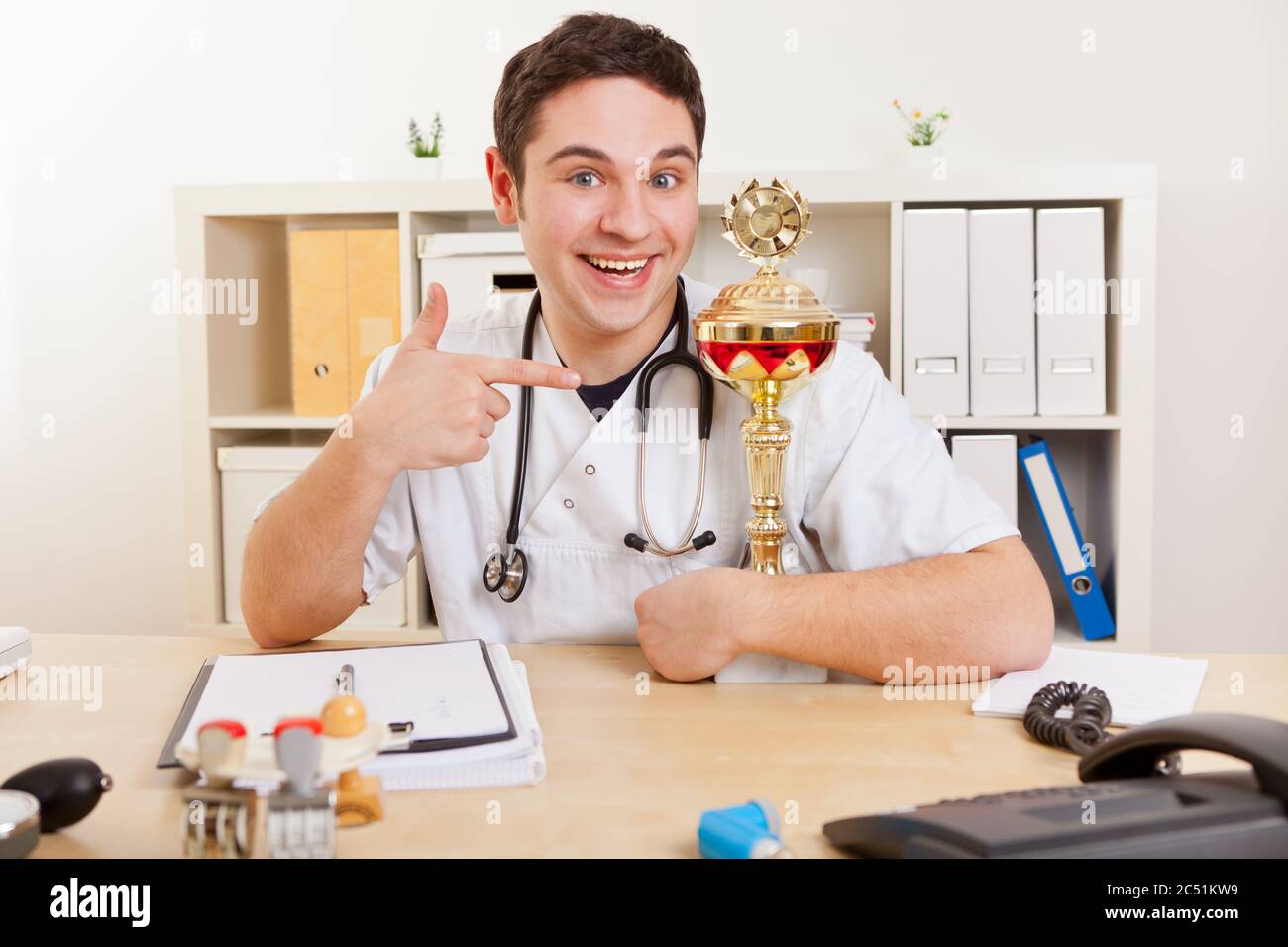 Laughing doctor in the office points to a cup Stock Photo - Alamy