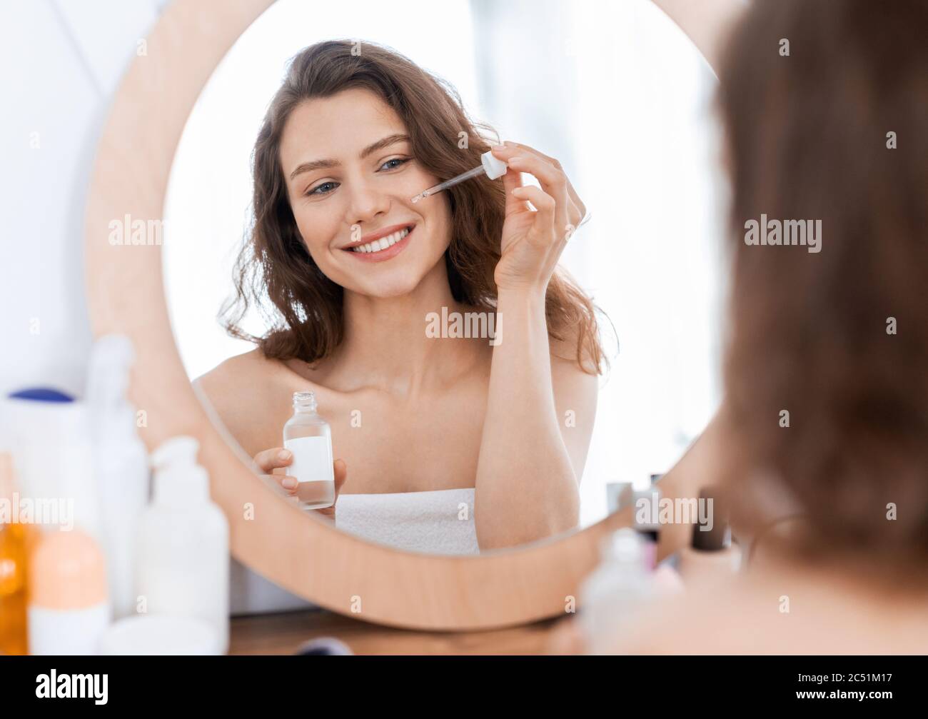 Cheerful girl using serum for hydrating skin at summer Stock Photo - Alamy