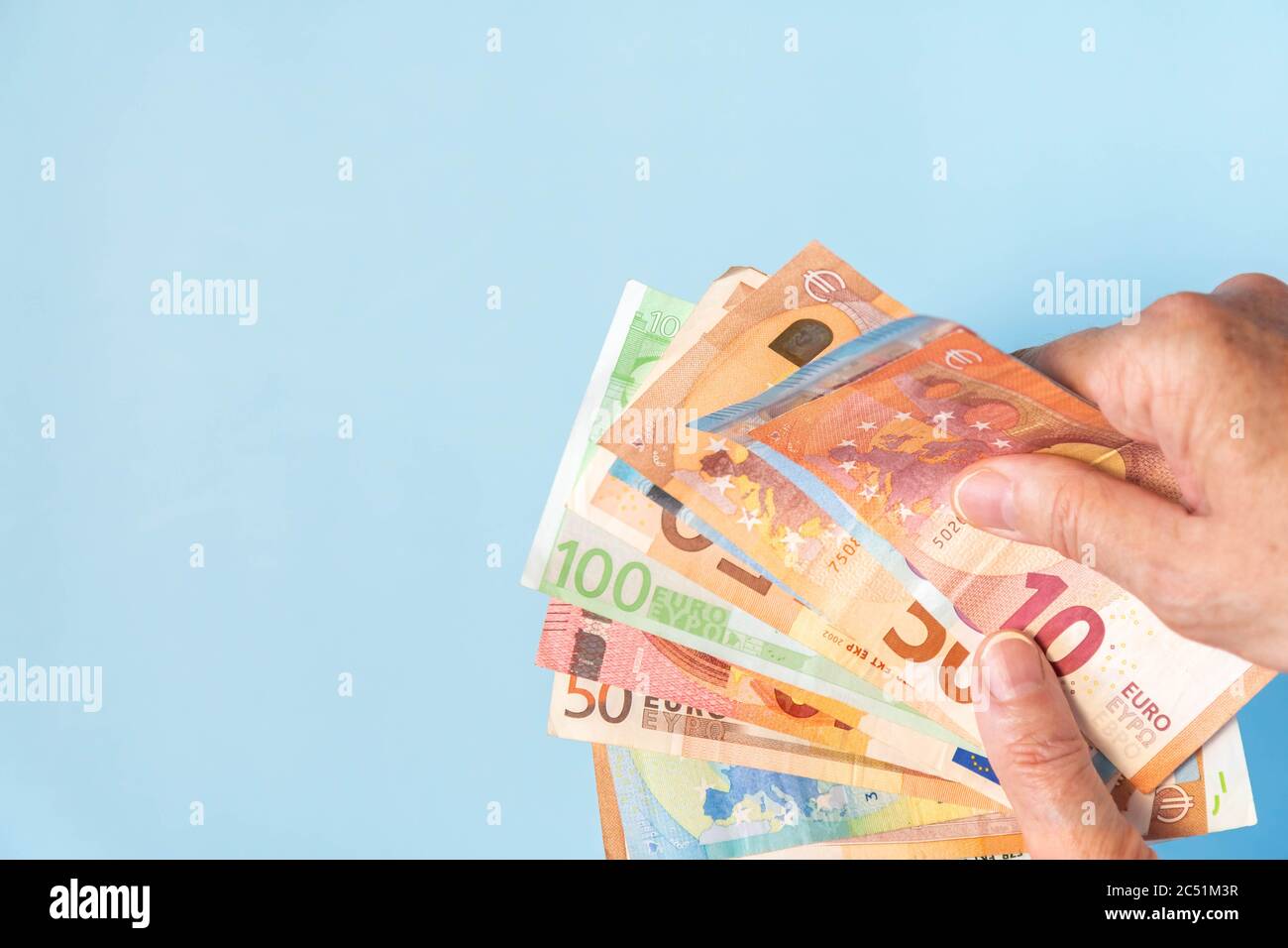 Hands holding European banknotes isolated on blue background. Person ...