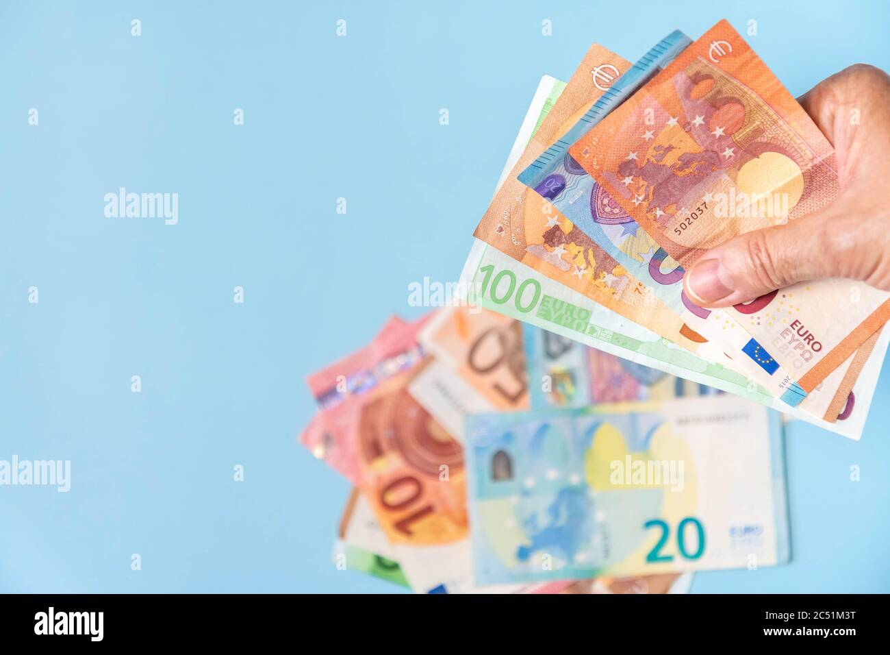 Person hand holding euro notes and other blurred banknotes on blue ...