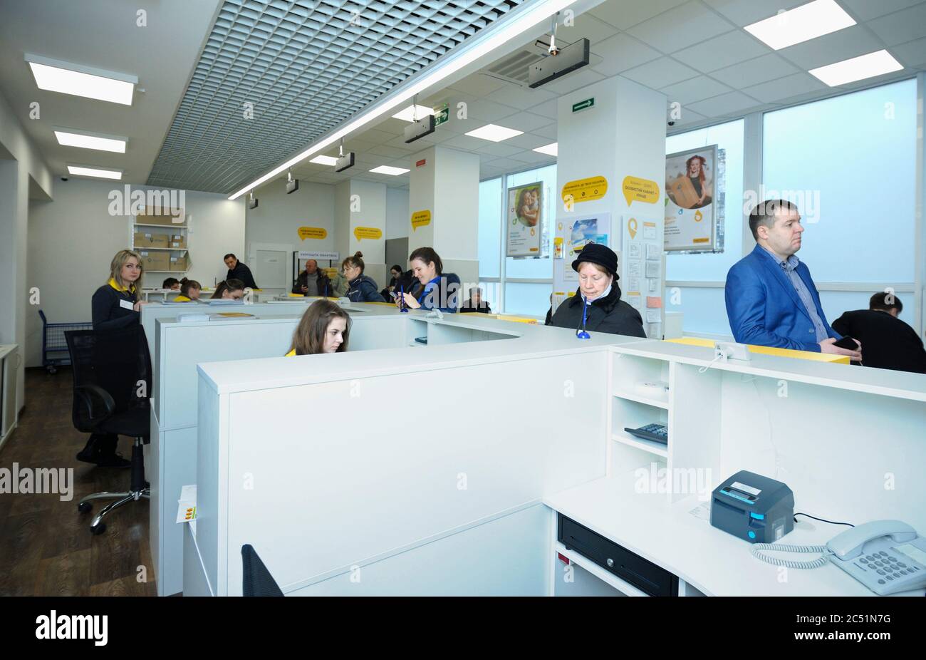 At the post office, reception: postal worker sitting at the desk set ...