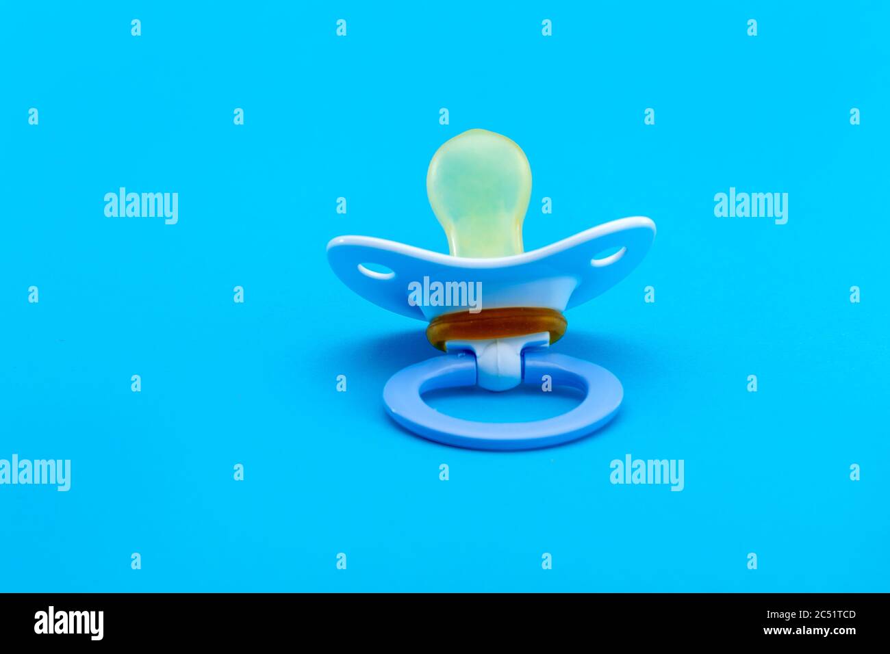 a blue pacifier made of soft silicone isolated on blue background back ...
