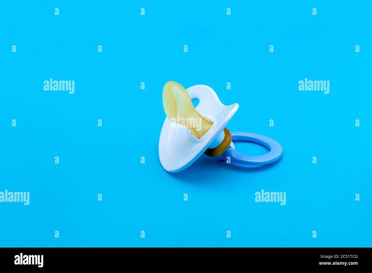 a blue pacifier made of soft silicone isolated on blue background side ...