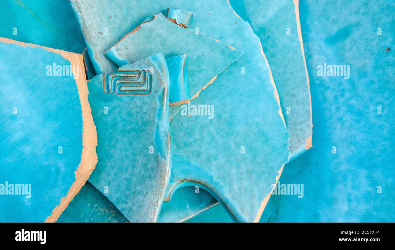 Overhead shot of a light blue broken ceramic plate lying on the ground ...