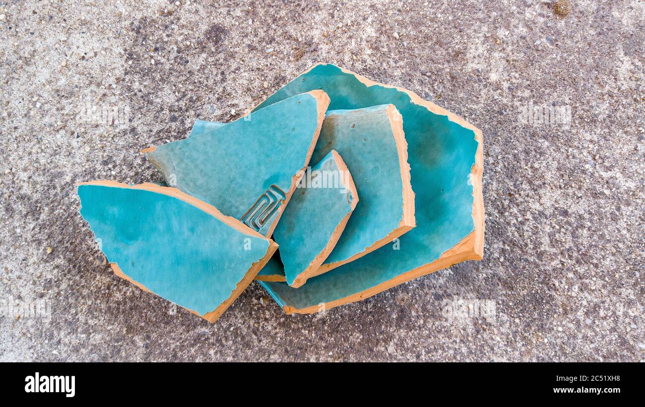 Overhead shot of a light blue broken ceramic plate lying on the ground ...