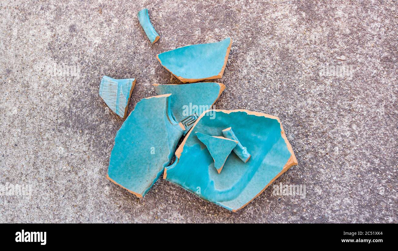Overhead shot of a light blue broken ceramic plate lying on the ground ...