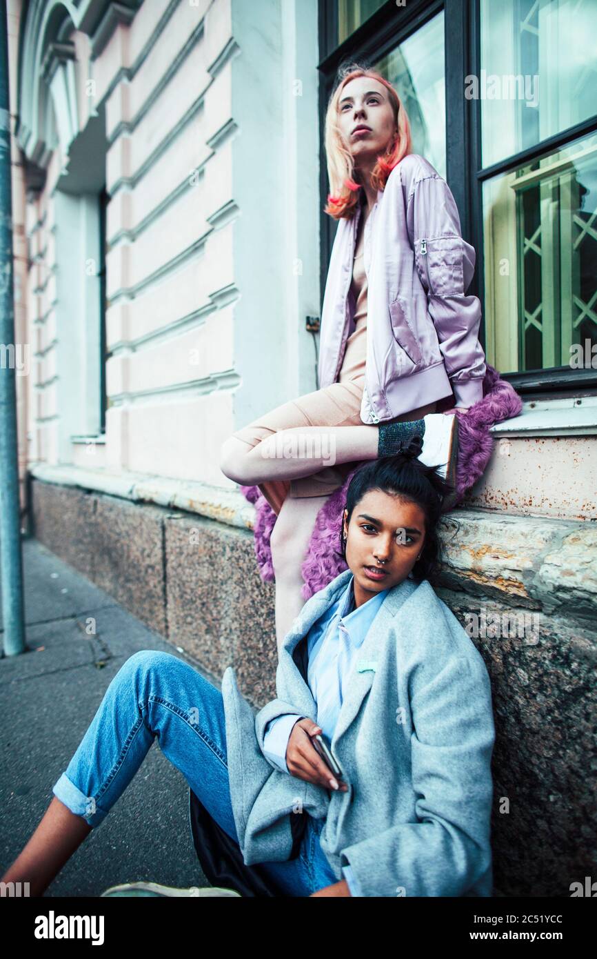 Two teenage girls infront of university building smiling, having fun ...