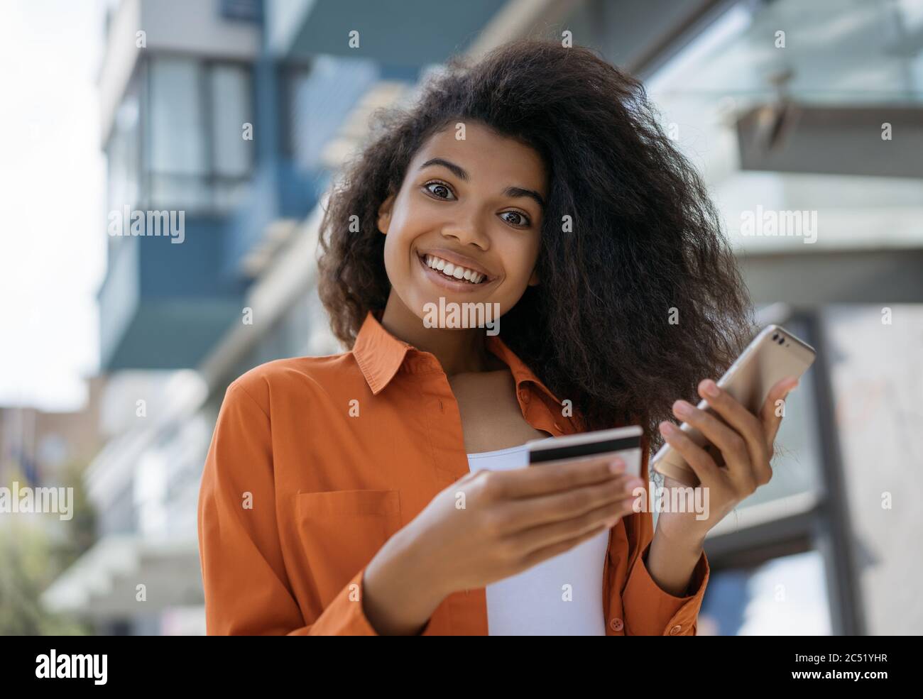 African American woman holding credit card, using smartphone with ... African American woman holding credit card, using smartphone with ...