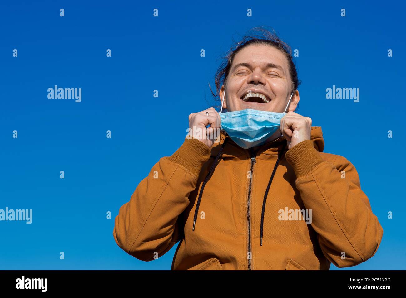 Close-up portrait of a satisfied man taking off his medical mask and ...