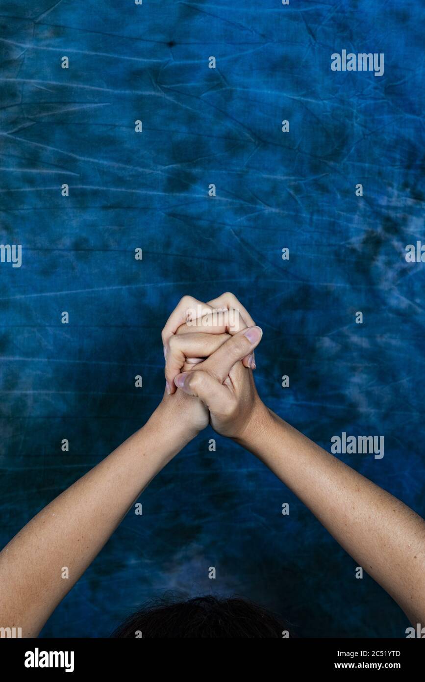 Horizontal shot of two hands locked together on a marbled blue ...