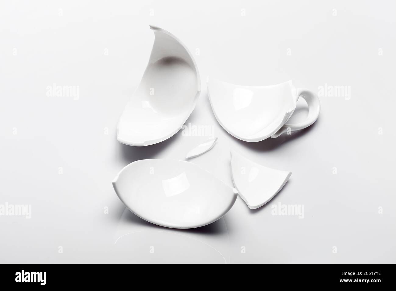 broken white ceramic tea cup on a white background, conceptual photo ...