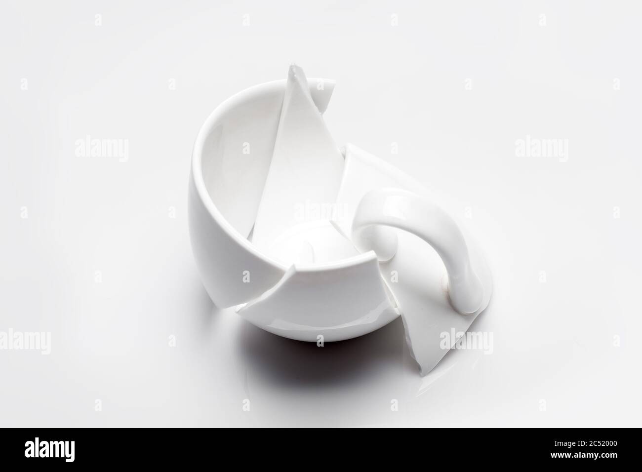 broken white ceramic tea cup on a white background, conceptual photo ...