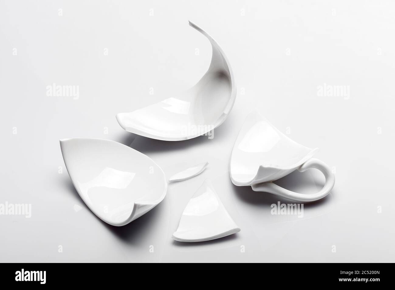 shattered white ceramic tea cup on a white background, concept on the ...