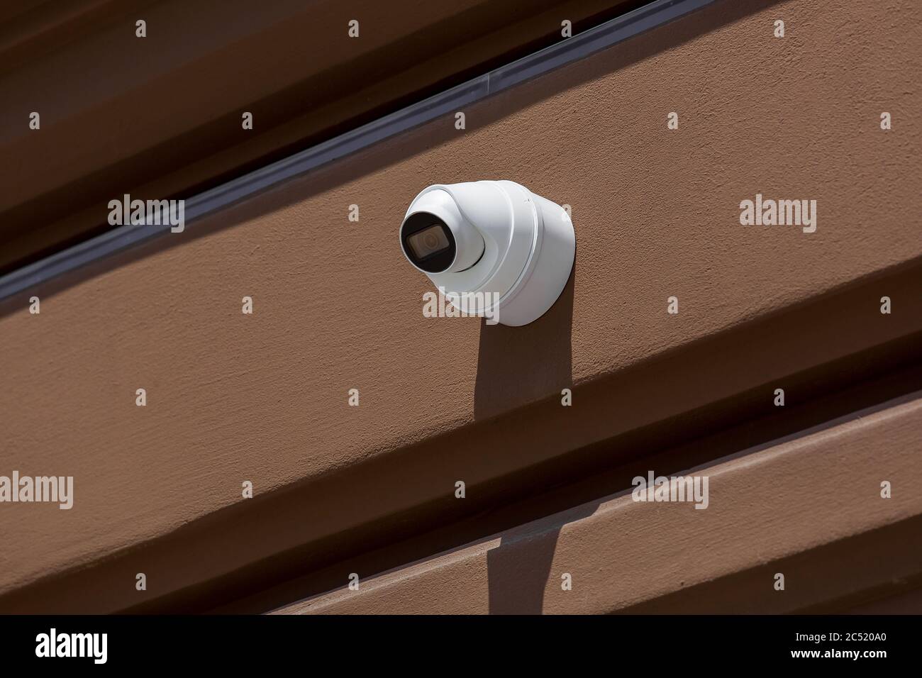 white CCTV camera installed on the exterior facade a brown building ...
