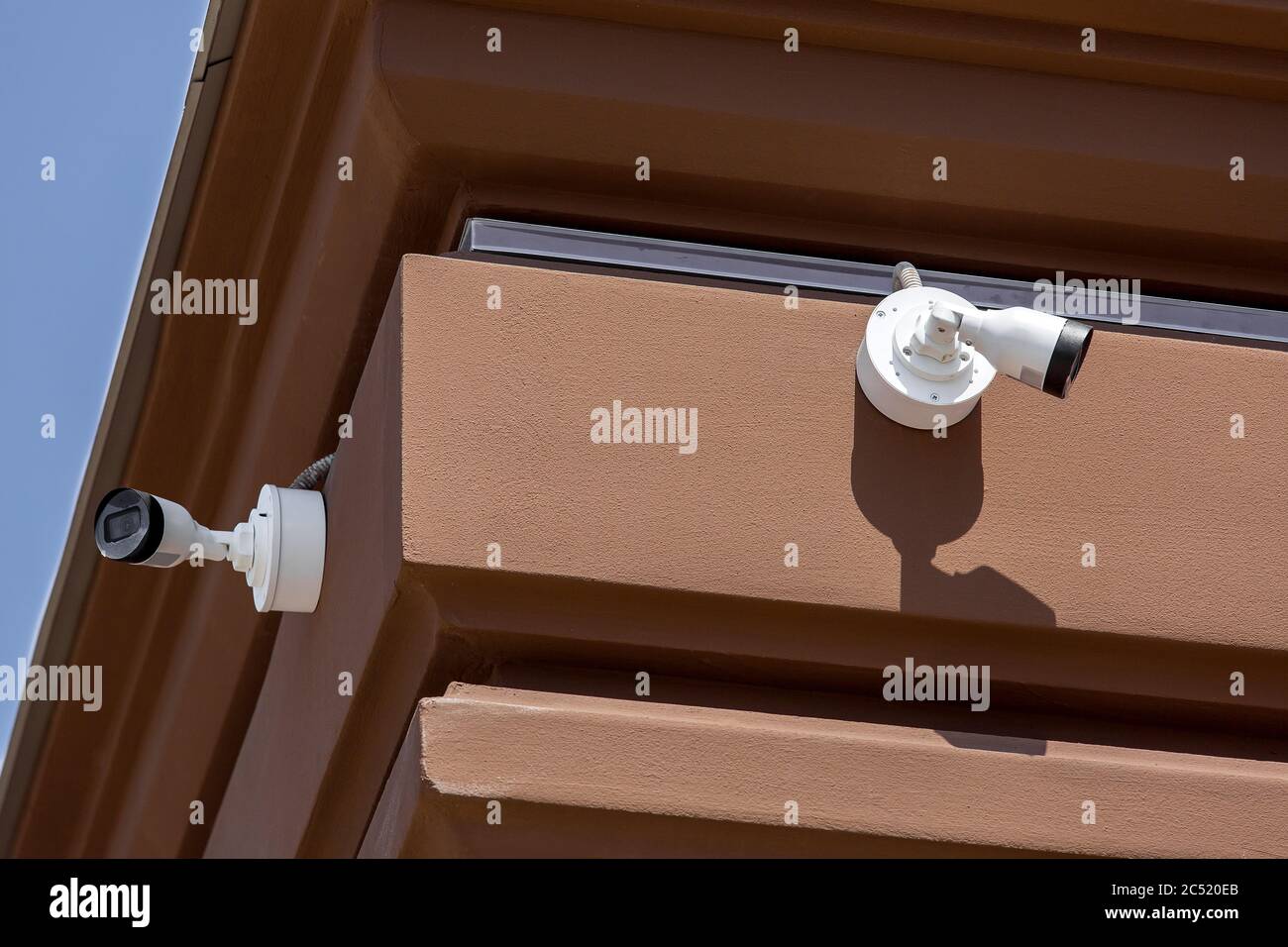 White color CCTV cameras mounted on the facade of a brown building ...