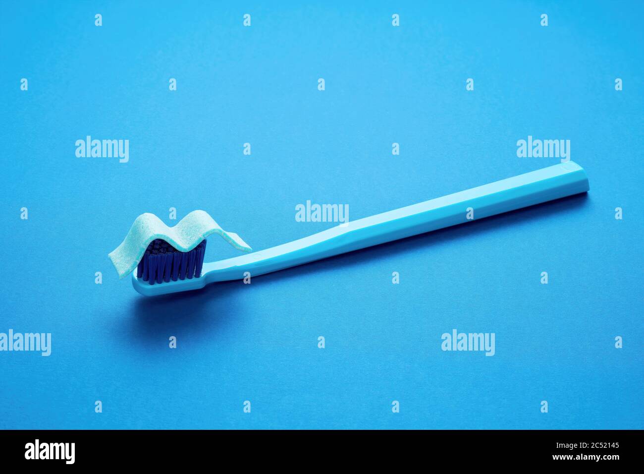 Toothbrush and chewing gum representing toothpaste on blue background ...