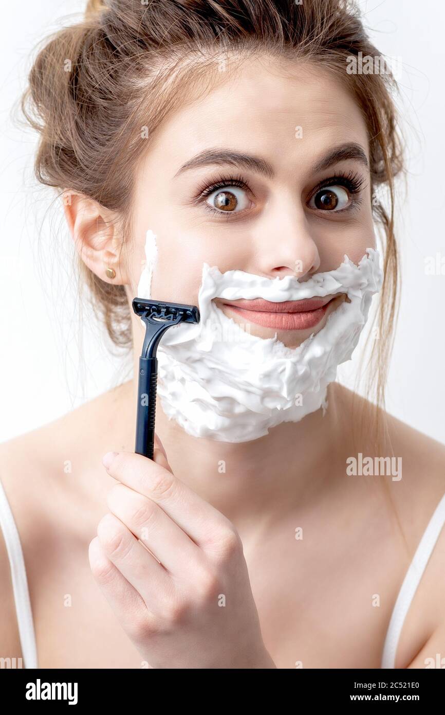 Beautiful young caucasian woman shaving her face by razor on white ...