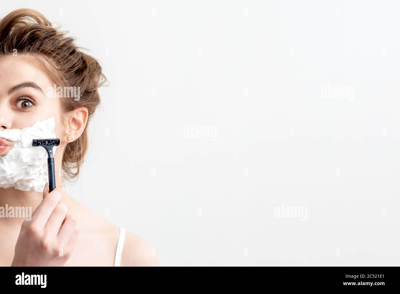 Beautiful young caucasian woman shaving her face by razor on white ...