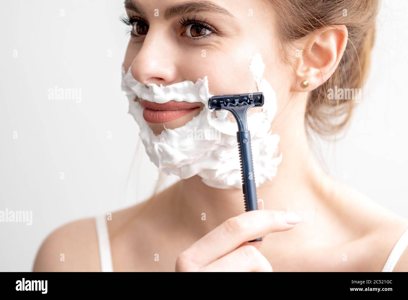 Beautiful young caucasian woman shaving her face by razor on white ...