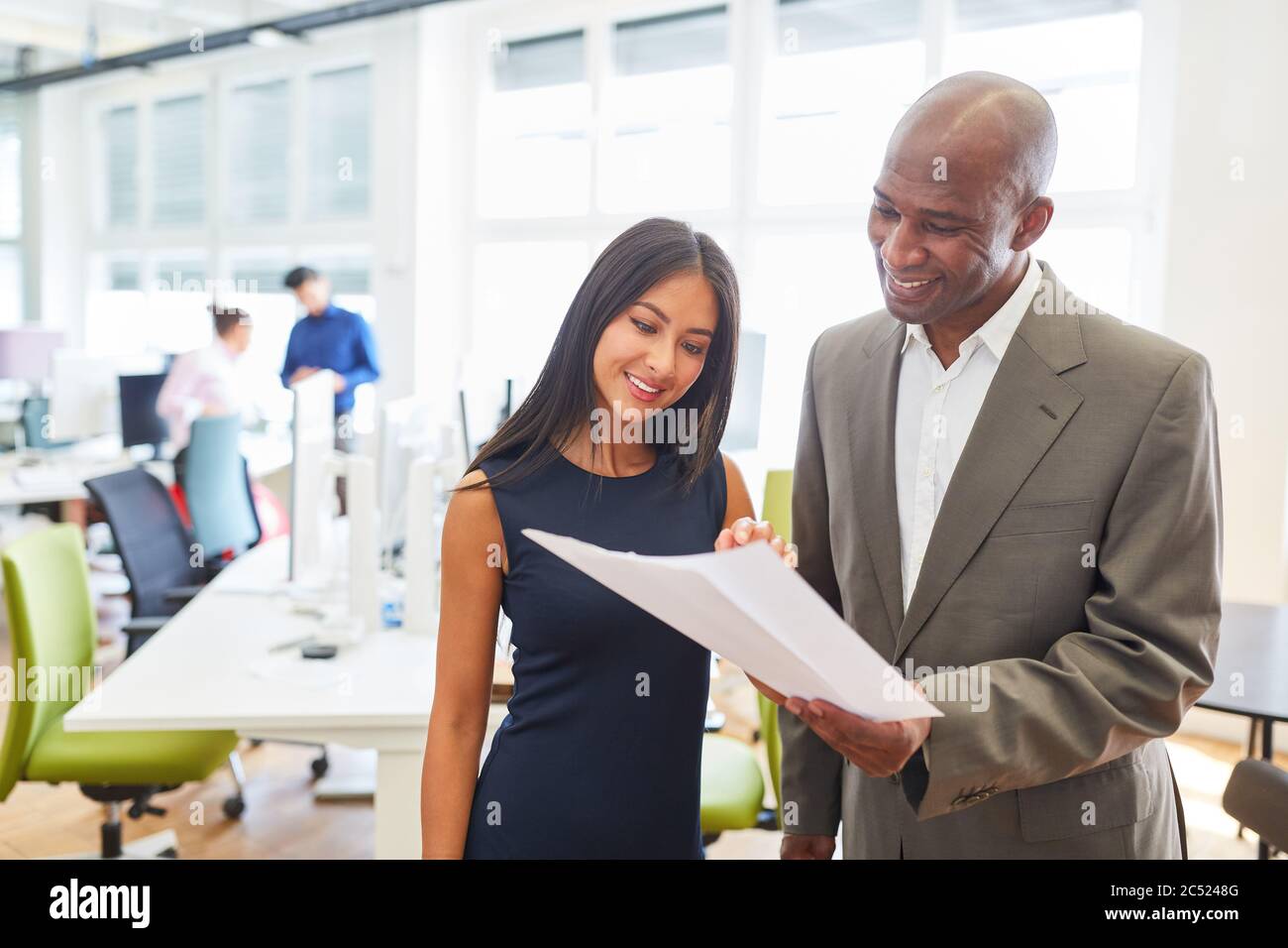 Two happy multicultural business people in the office working together ...
